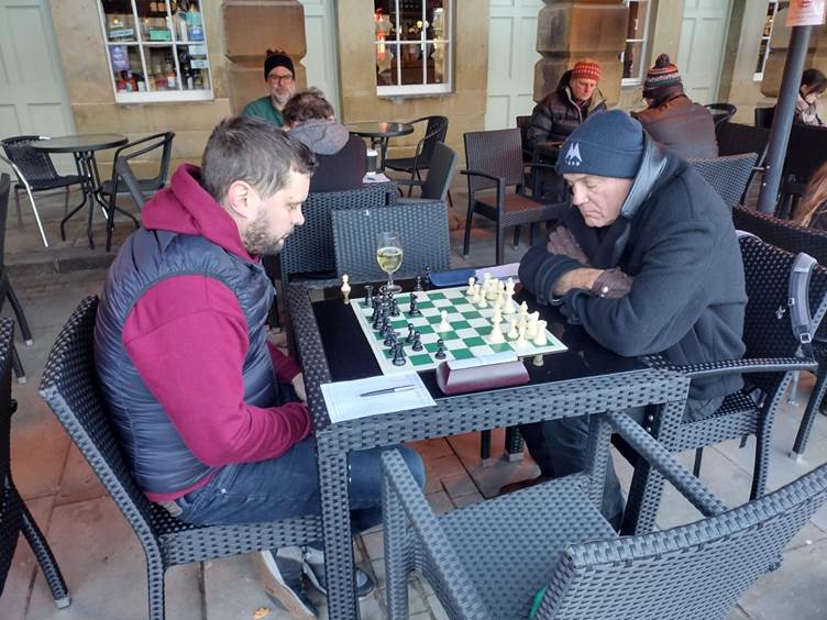Two men playing chess outsideDescription automatically generated